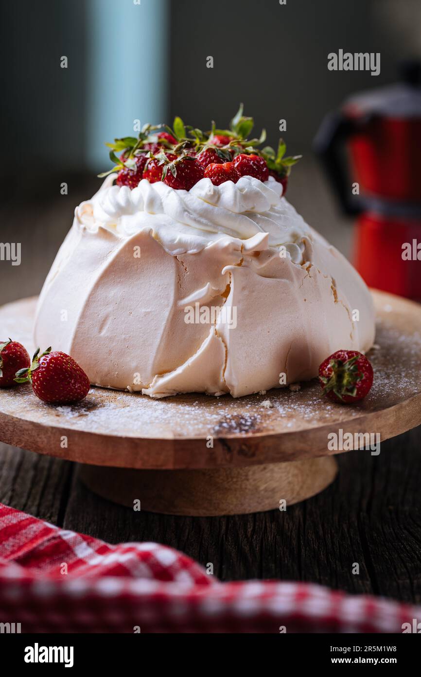 Pavlova cake decorated with strawberries on rustic wooden table surface ...