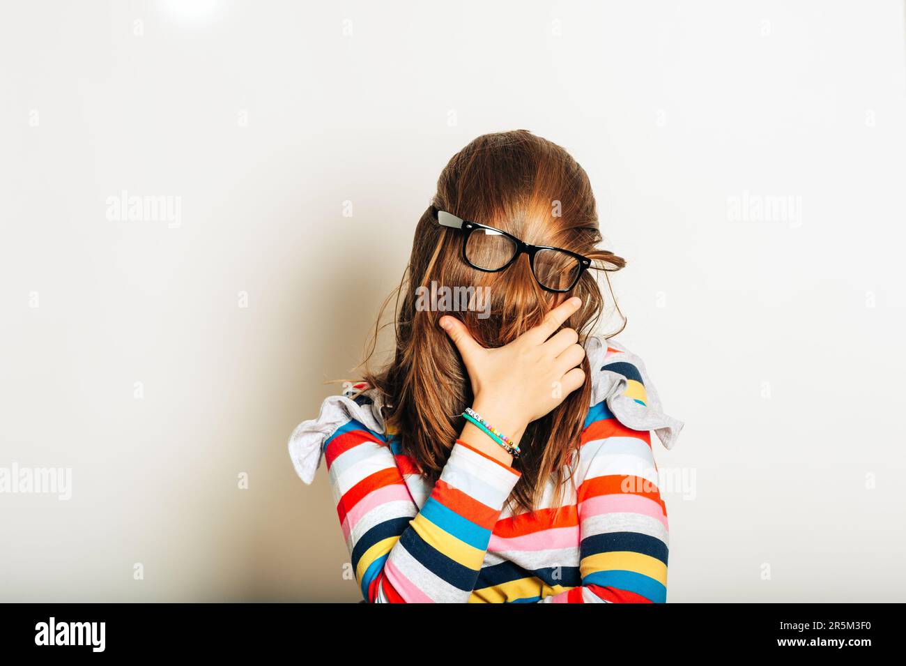 Studio portrait of young girl fooling around, hiding behind, hair ...