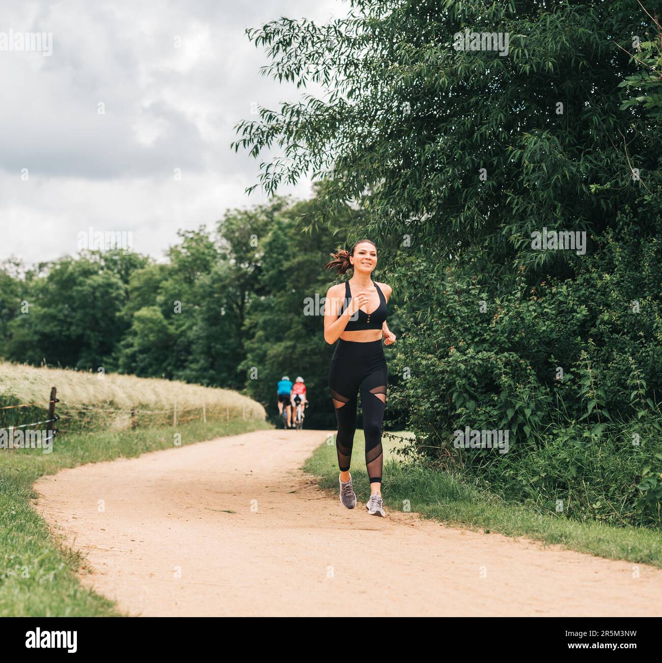 Portrait of young beautiful fit woman jogging in nature, wearing black ...