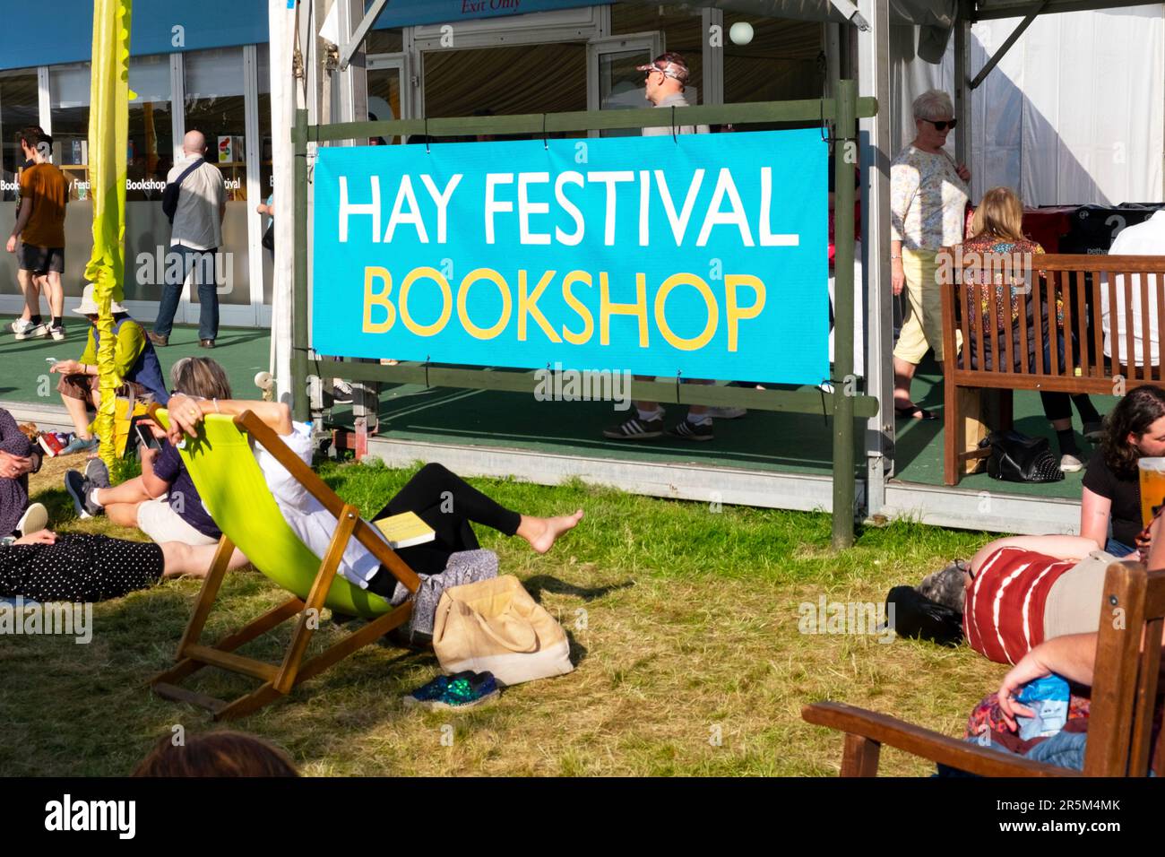 People relaxing in deckchairs and sitting on the grass outside by the ...