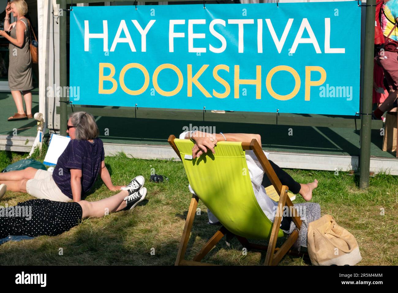 People relaxing in deckchairs and sitting on the grass outside by the ...