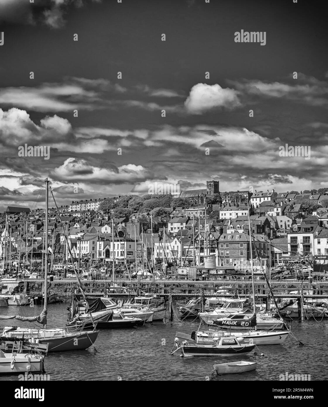 A harbour and marina are in the foreground leading to a seaside town ...