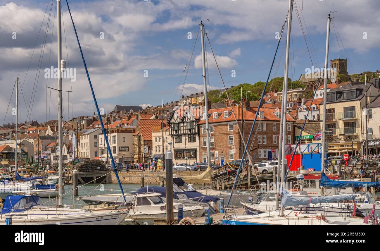 A harbour and marina are in the foreground leading to a seaside town ...