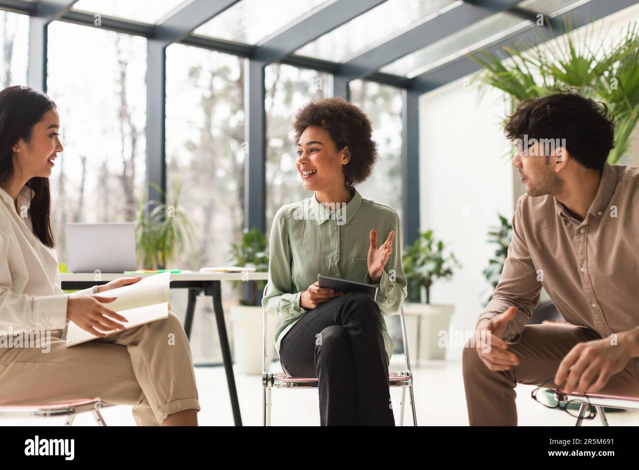 Three Young Coworkers Talking Engaging in Collaboration Sitting At ...
