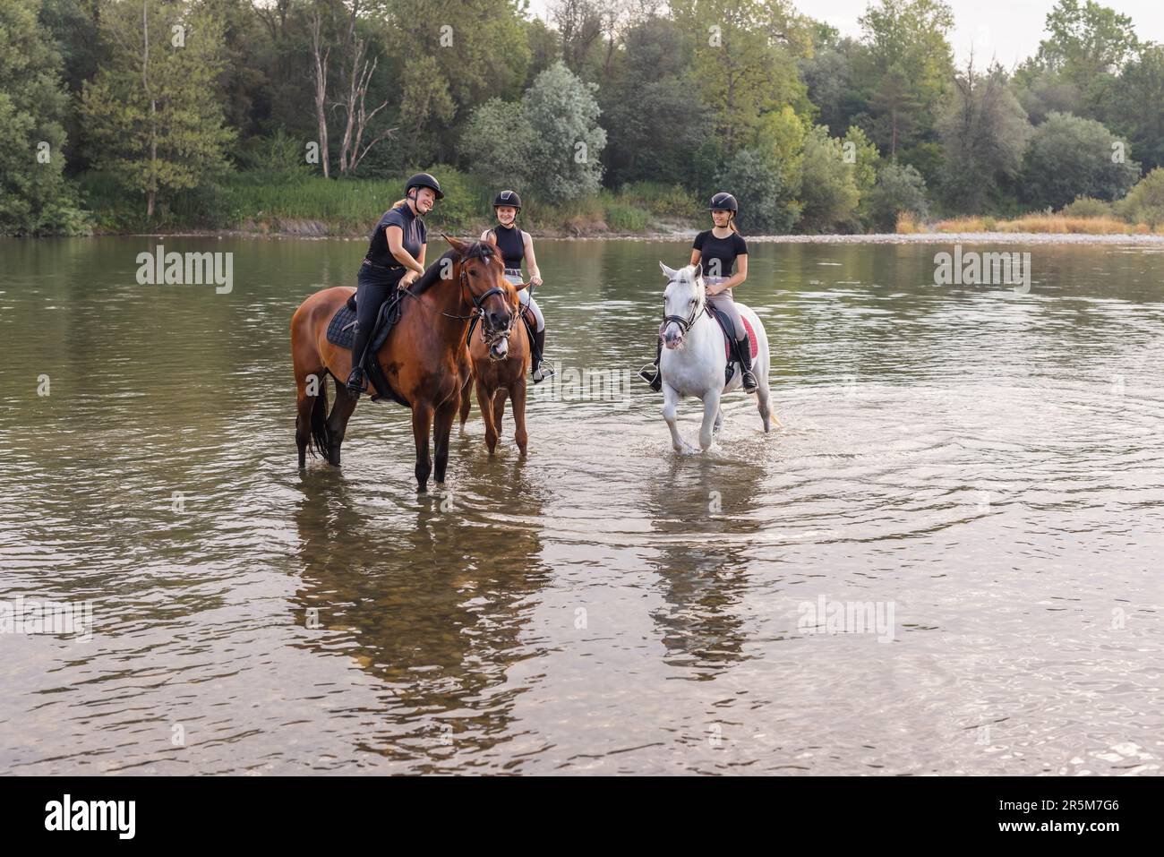 Three young women enjoying equestrian leisure, nature, and river ...