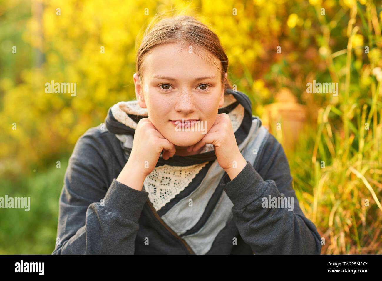 Outdoor close up portrait of young teen girl leaning head on hands ...