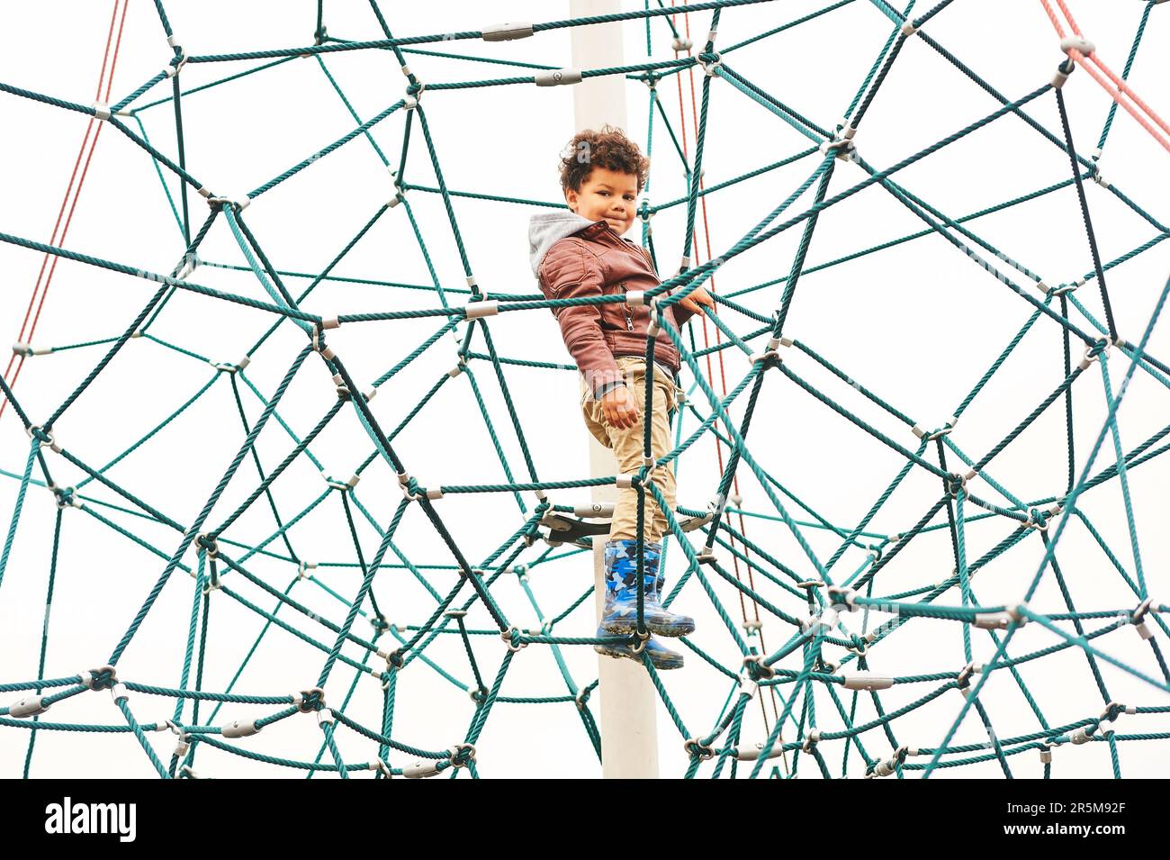 Little kid boy on the top of climbing net, playground activities for ...