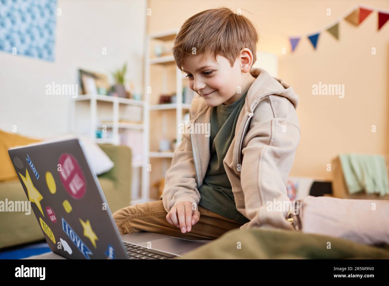 Side view portrait of smiling boy looking at computer screen while ...