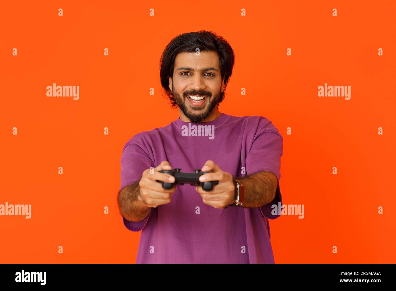 Happy indian guy playing video game, holding joystick, orange ...