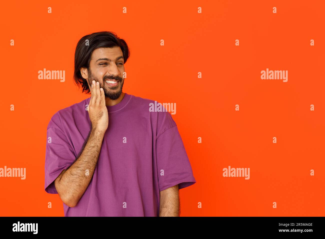 Sceptical eastern guy looking at copy space, touching face Stock Photo ...