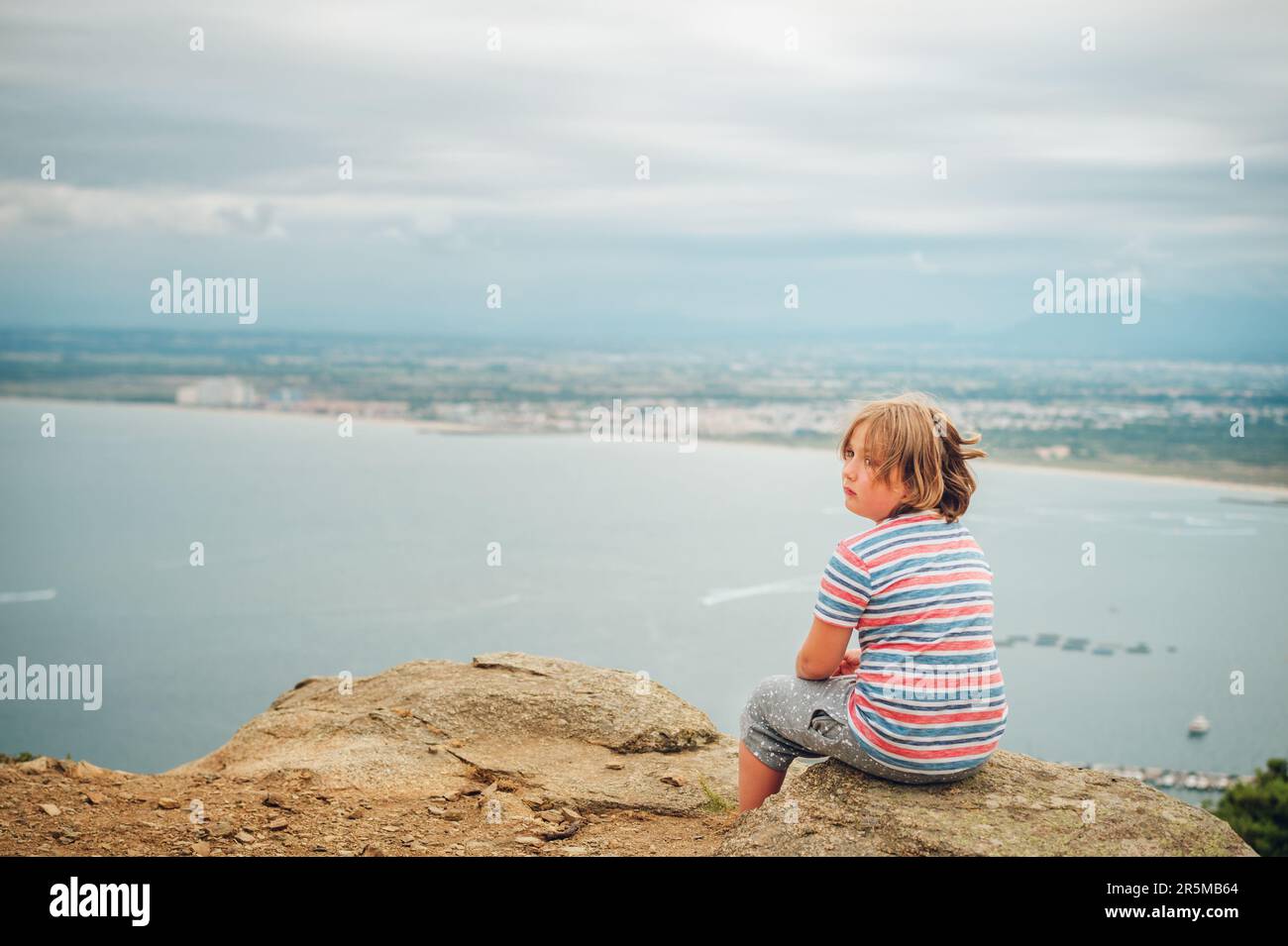 Little boy resting on the top of mountain, admiring sea landscape Stock ...