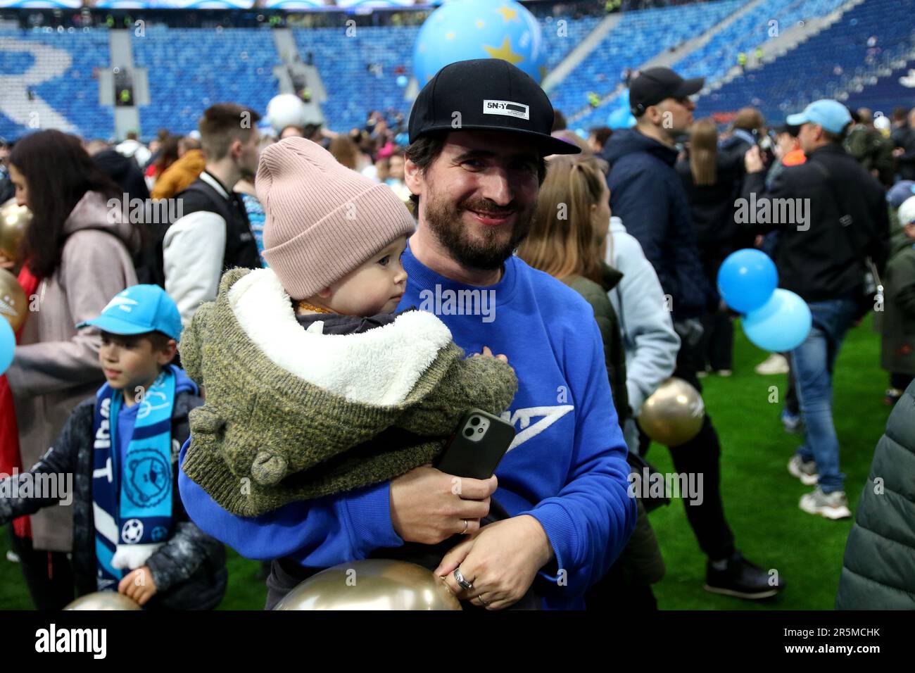 A man and a baby pose on a football field surrounded by balloons. Zenit ...
