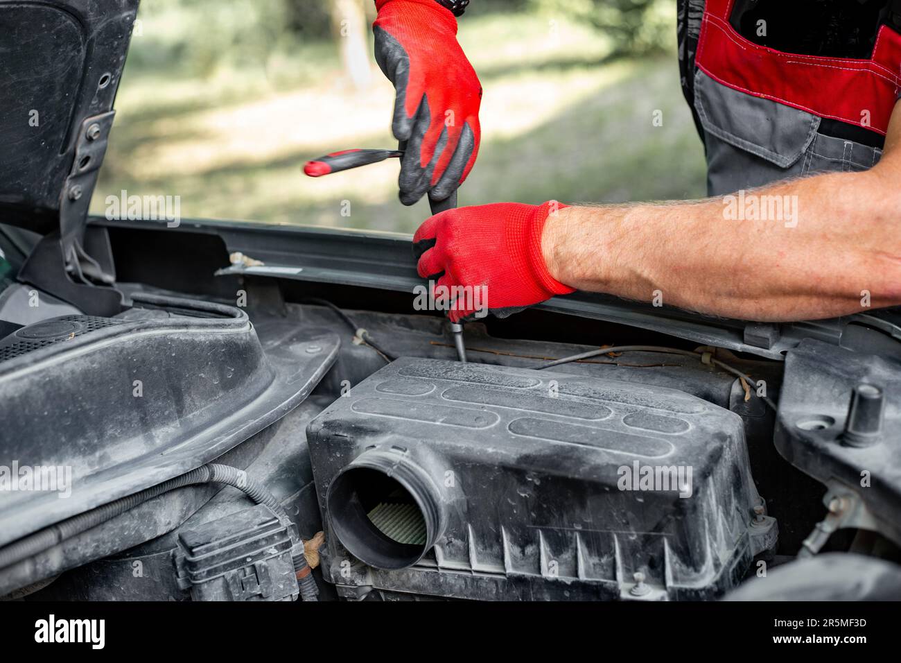An auto mechanic opens the air filter housing of an internal combustion ...