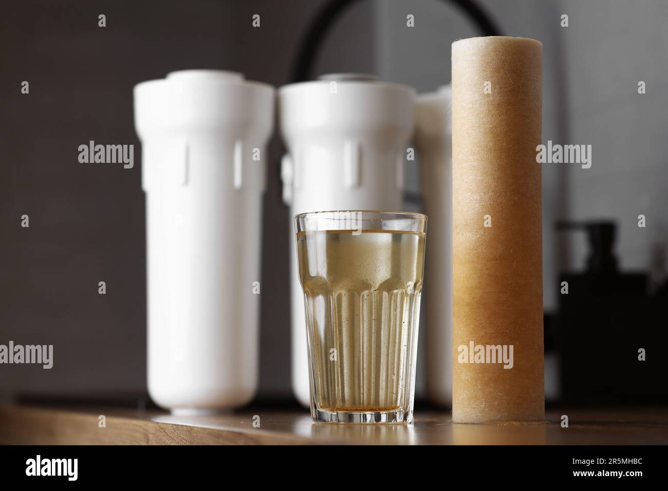 Water filter cartridge used and a glass of rusty water brown coloring ...