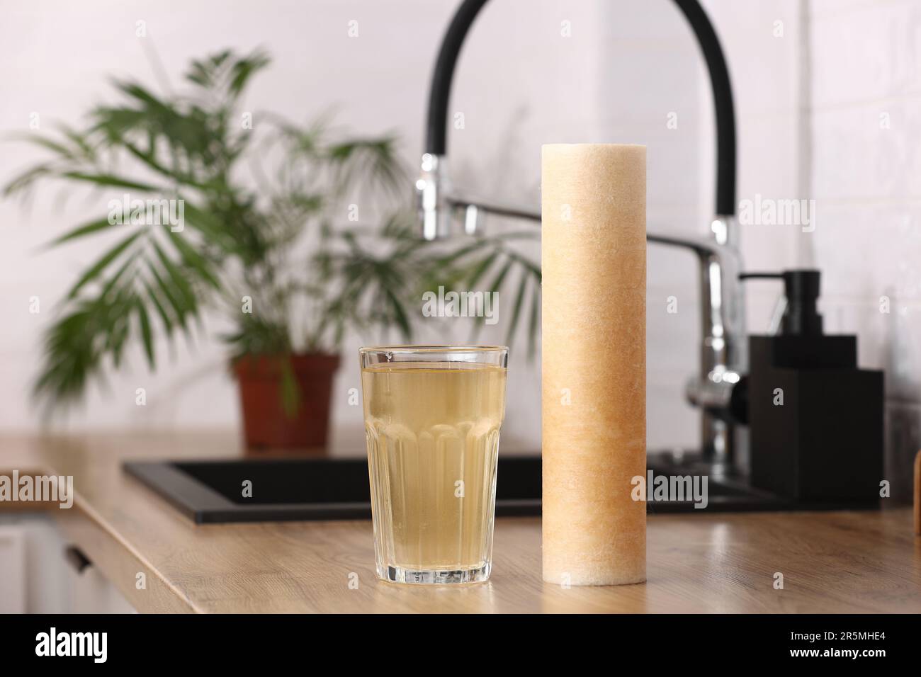 Used cartridge in rust and glass of dirty water on tabletop on kitchen ...