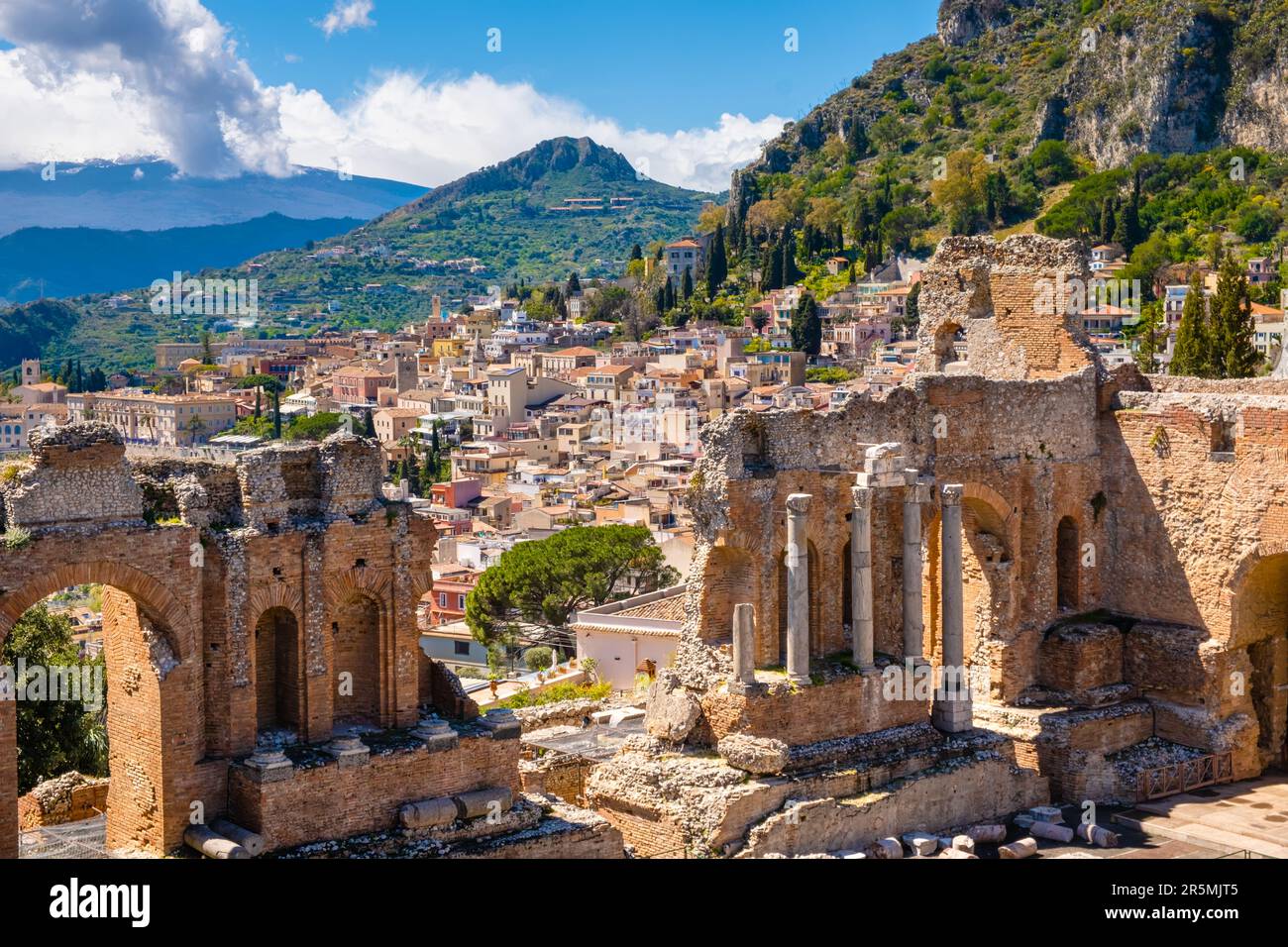 Taormina on Sicily, Italy. Ruins of ancient Greek theater, mount Etna covered with clouds ...