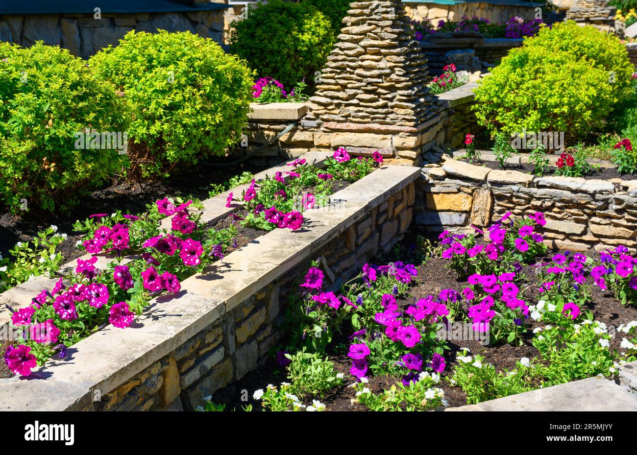 Landscaping with retaining walls and flowerbeds in residential house backyard. Landscape design ...