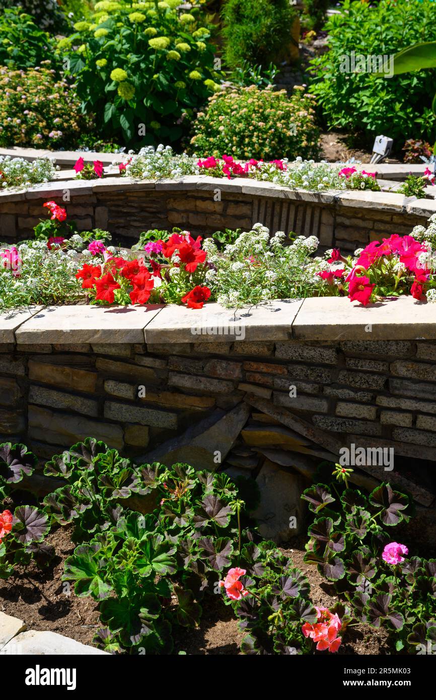 Landscaping with retaining walls and flowerbeds in residential house backyard. Landscape design ...