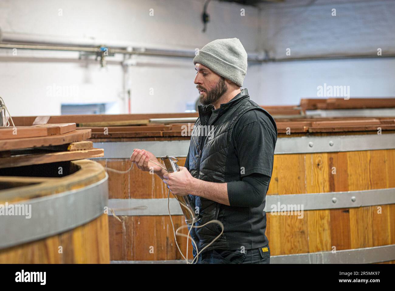 A distillery worker checking fermentation at the washbacks ...