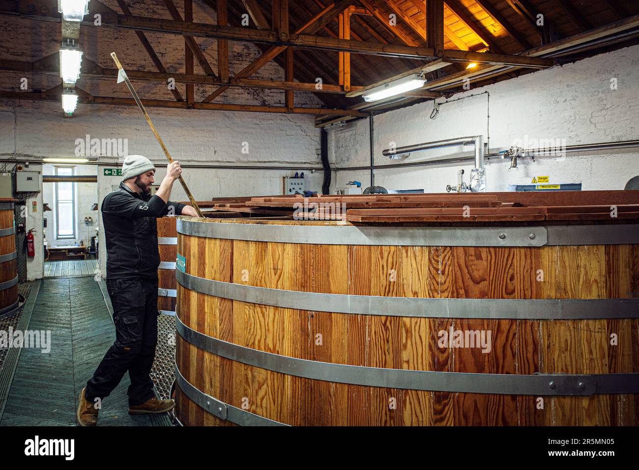 A distillery worker checking fermentation at the washbacks ...