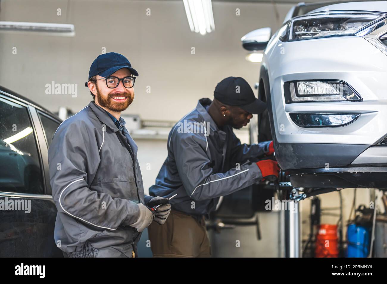 Car mechanics repairing car suspension in auto repair shop. High ...