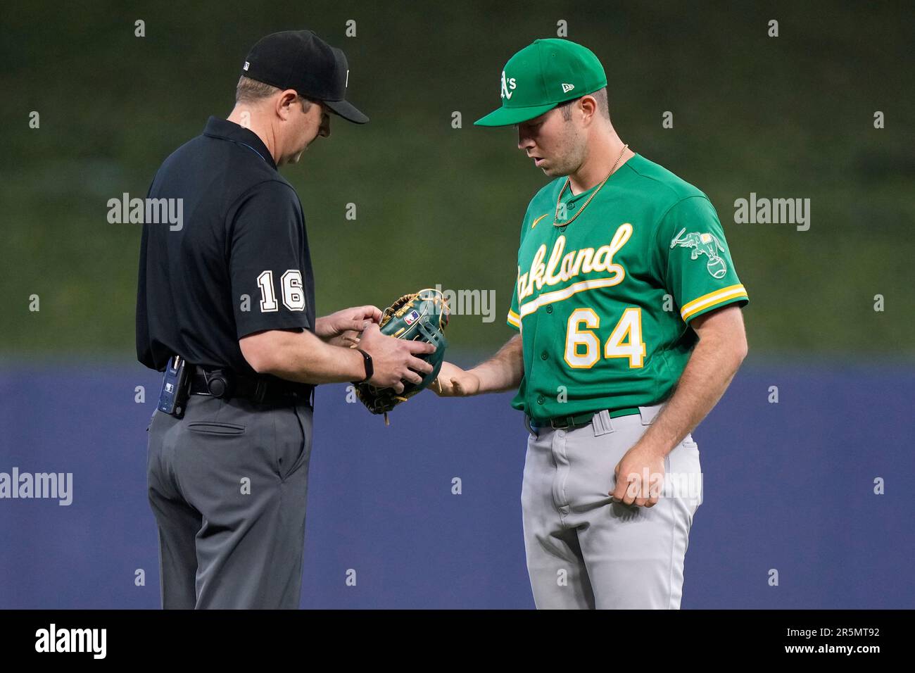 Official Lance Barrett, left, checks the glove of Oakland Athletics ...