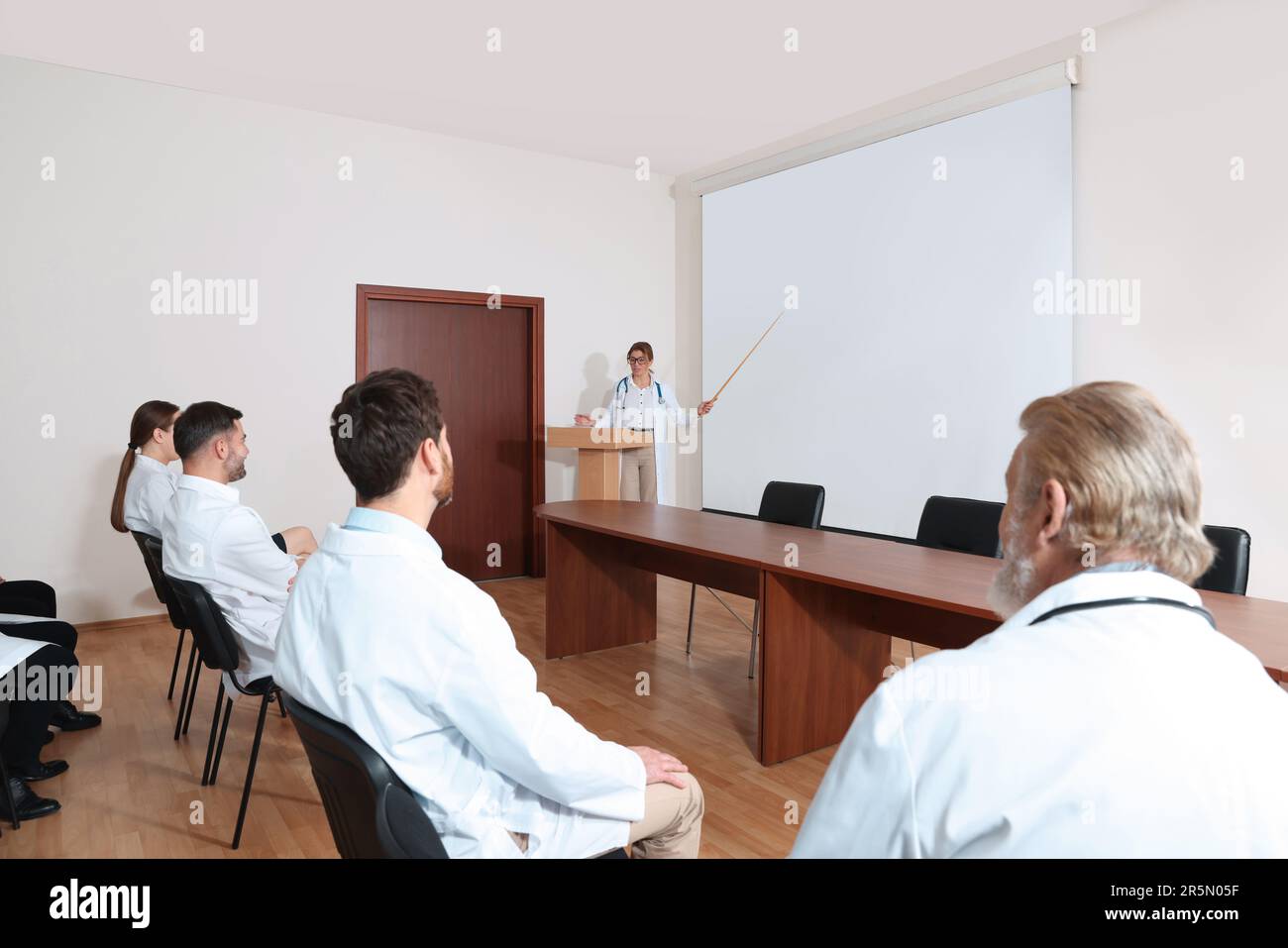 Doctor giving lecture in conference room with projection screen Stock ...