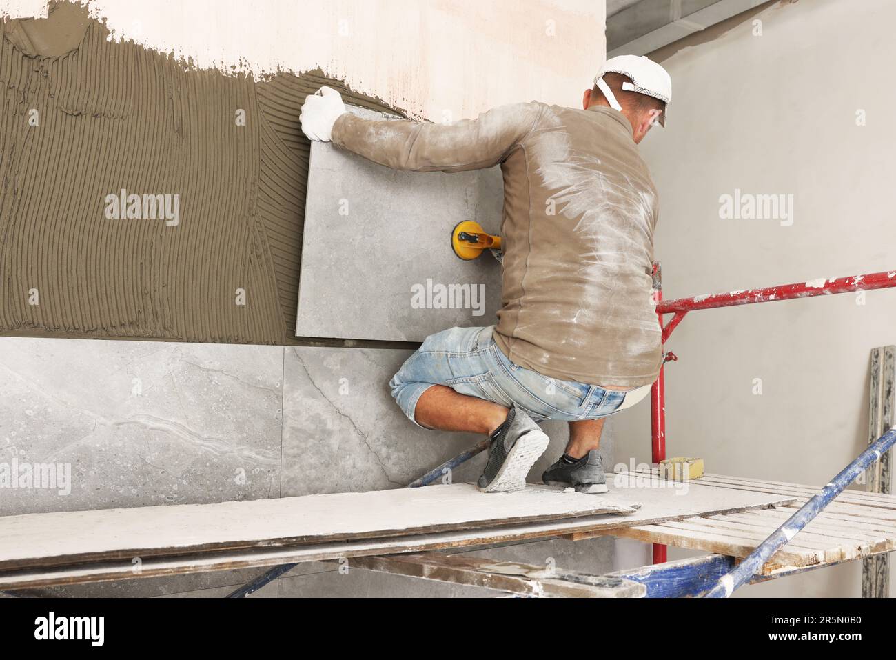 Worker installing wall tile with vacuum holder indoors, back view Stock ...