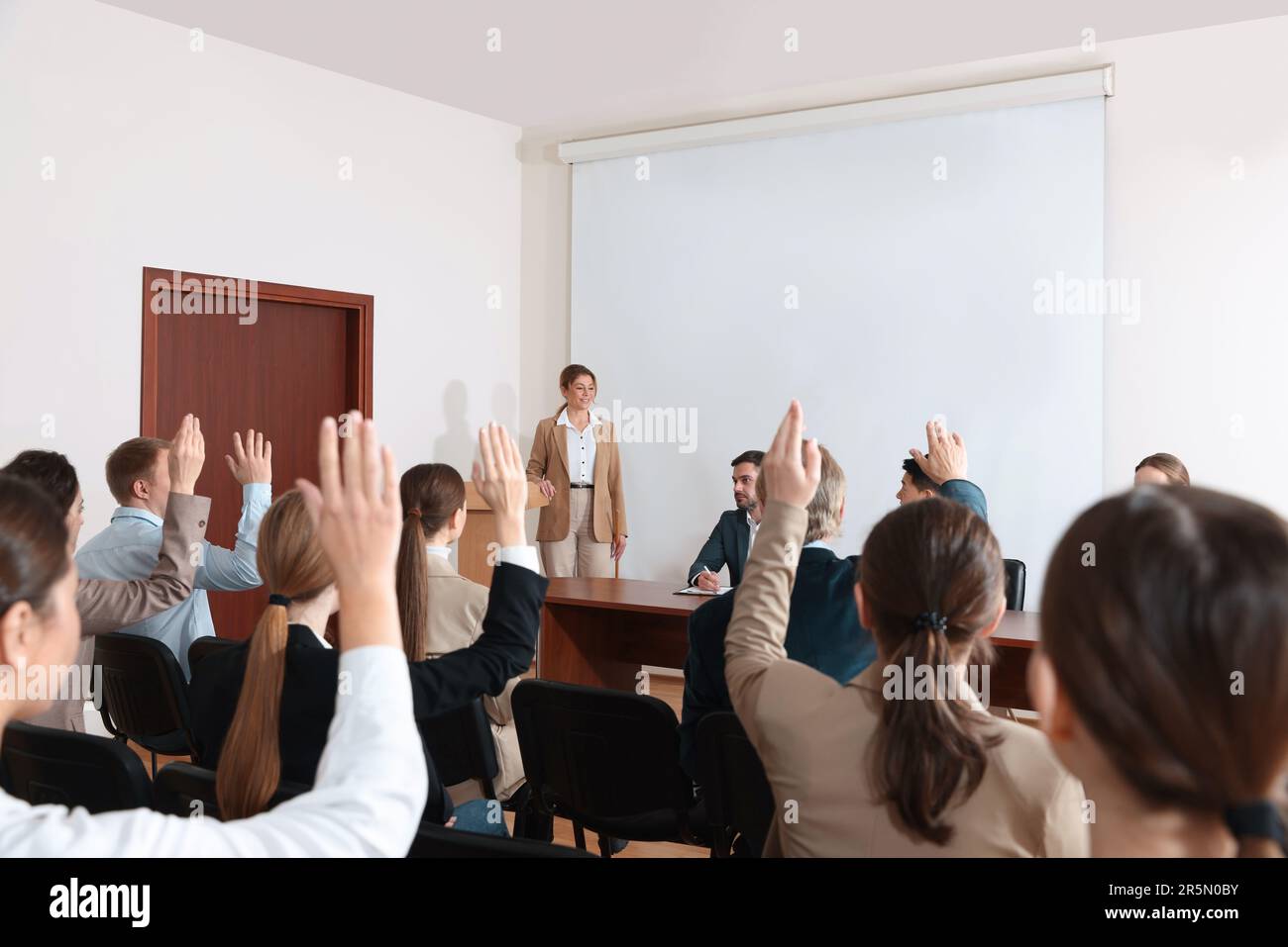 People raising hands to ask questions at business conference in meeting ...