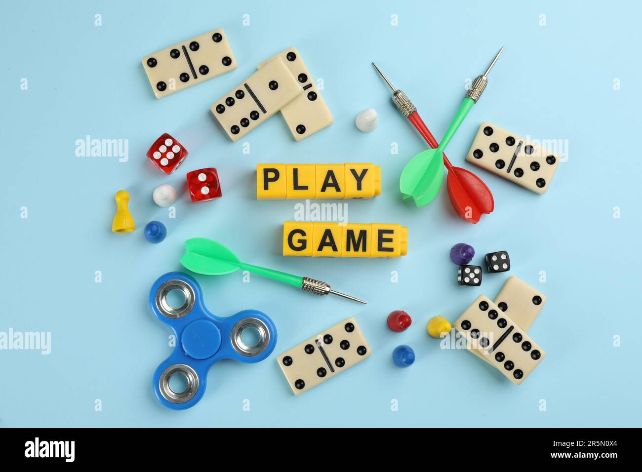 Flat lay composition of blocks with words Play Game on light blue ...