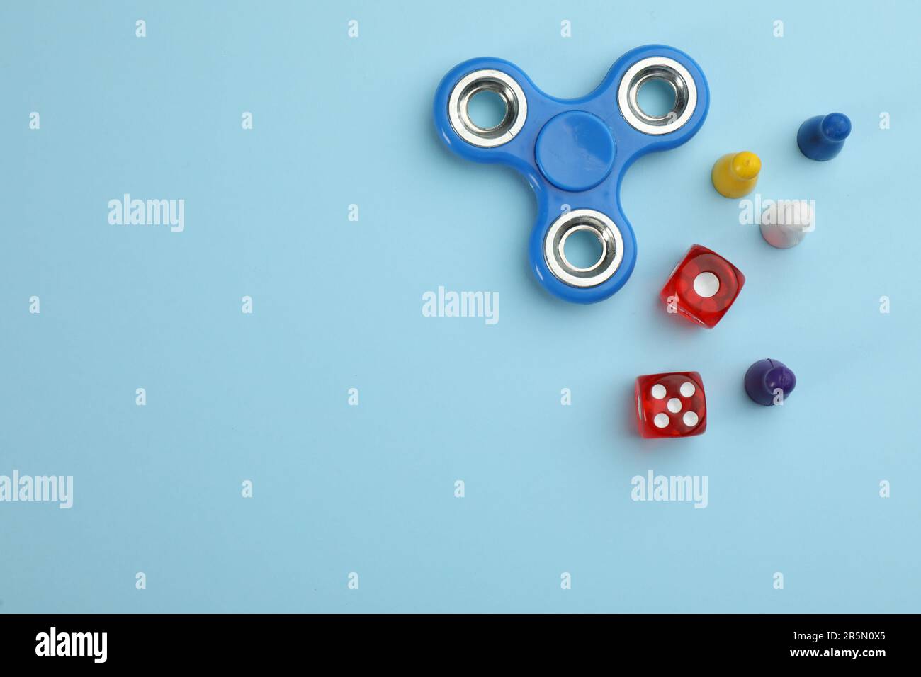 Spinner, dices and pawns on light blue background, flat lay with space ...
