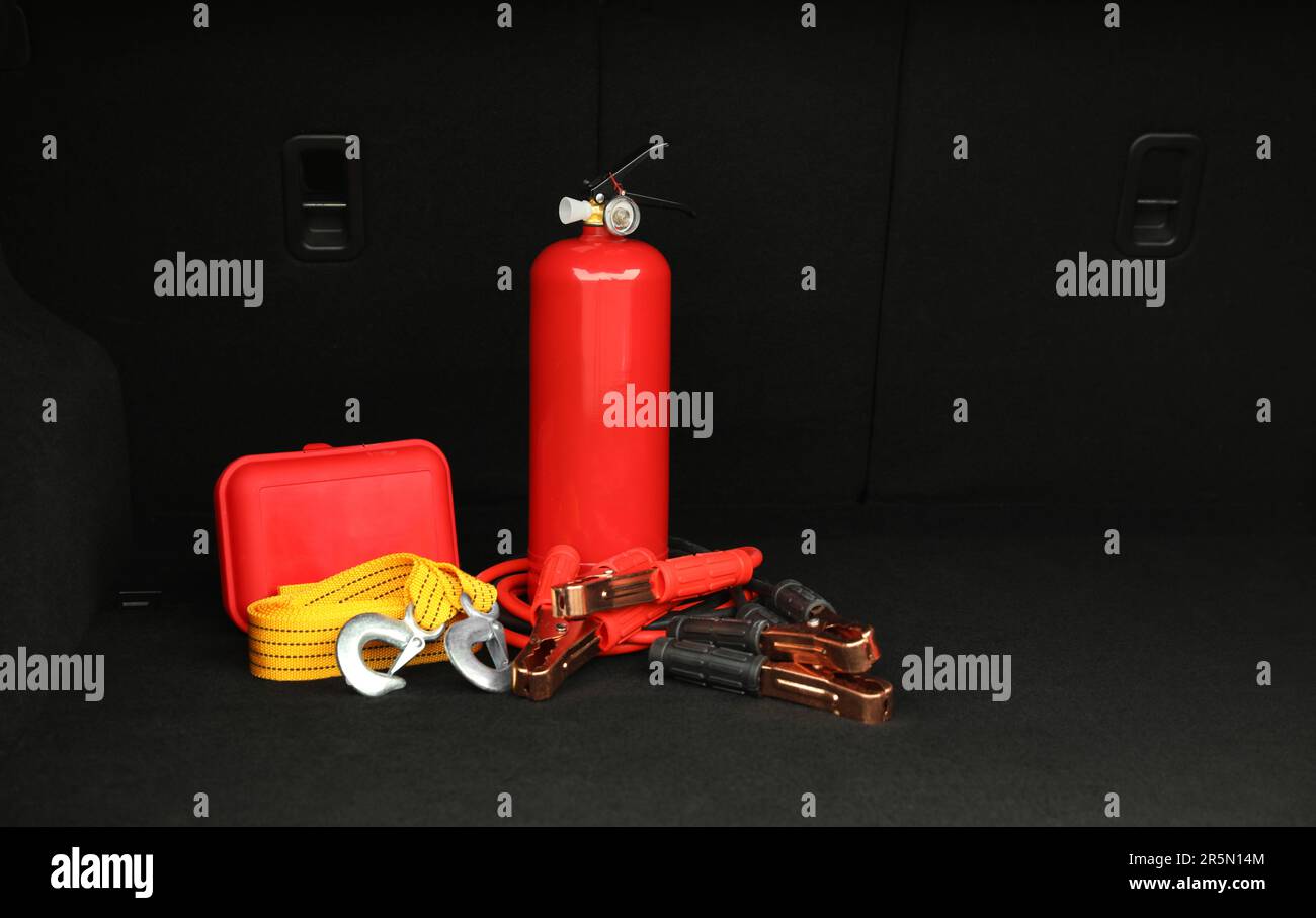 Red fire extinguisher, battery jumper cables, towing strap and first ...