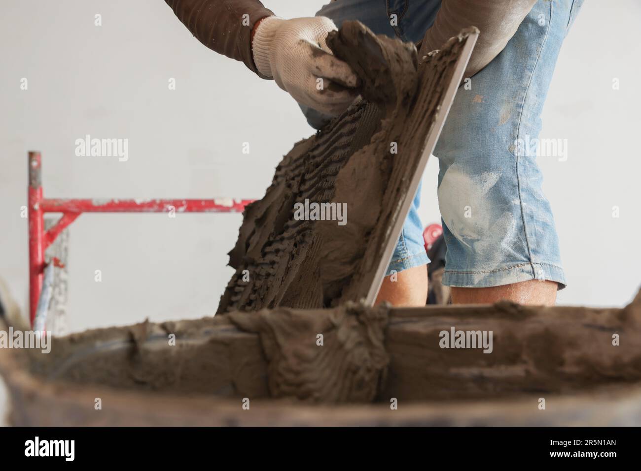 Worker applying cement on wall tile for installation indoors, closeup ...