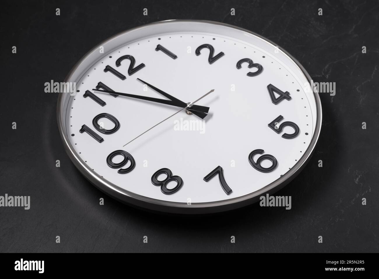 Clock showing five minutes until midnight on black table. New Year ...