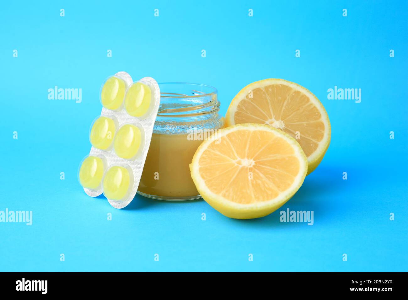 Blister with cough drops, fresh lemon and honey on light blue ...