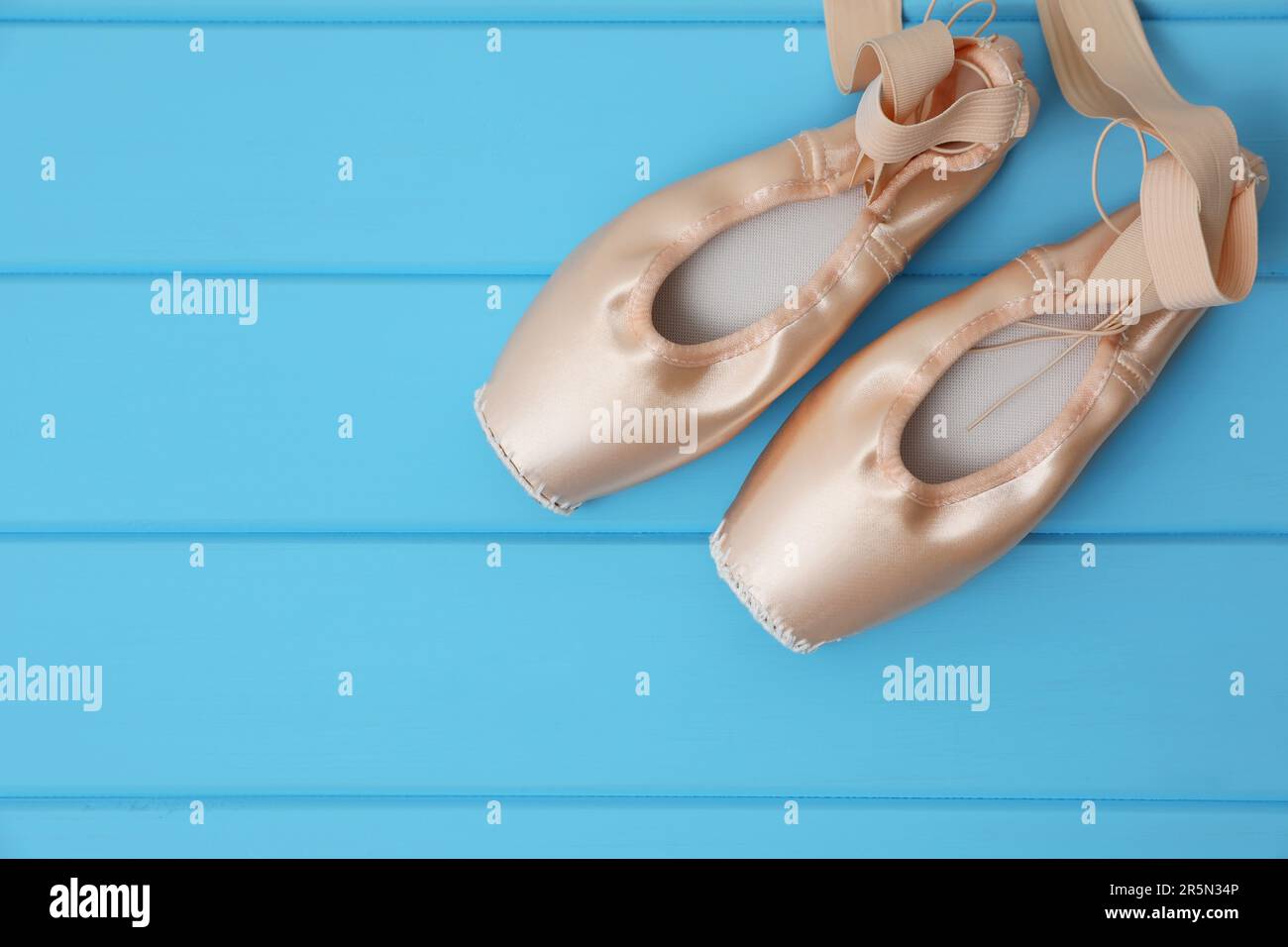 Beautiful beige ballet shoes with cute ribbons on light blue wooden ...