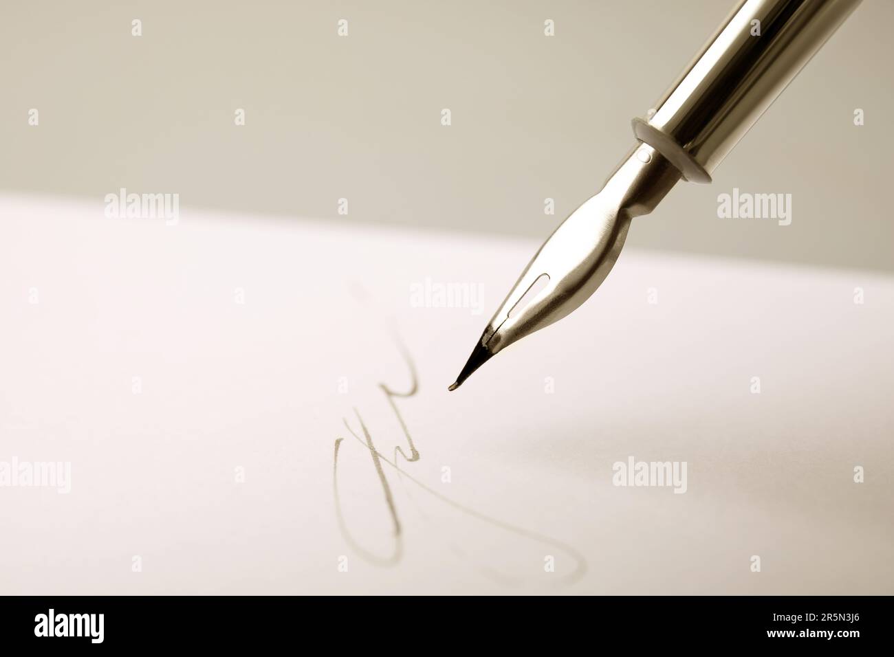 Signing on sheet of paper with fountain pen against light grey ...
