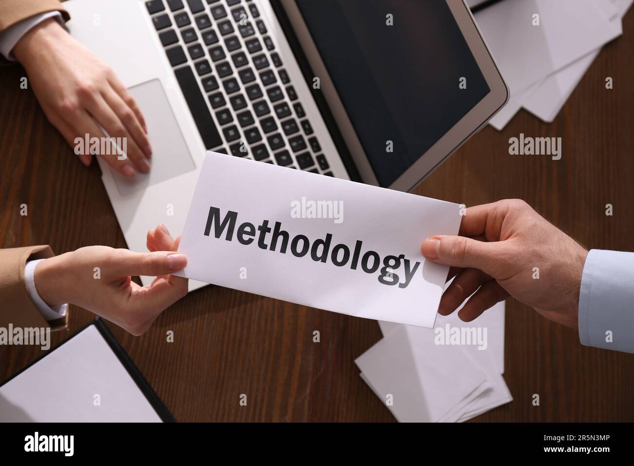 Worker giving paper with word Methodology to man in office, top view ...