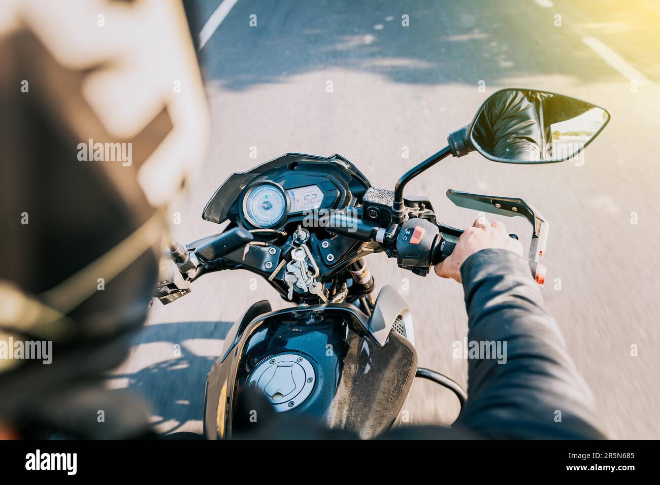 Close up of motorcyclist driving his motorbike on the street. View of hands of biker driving his ...