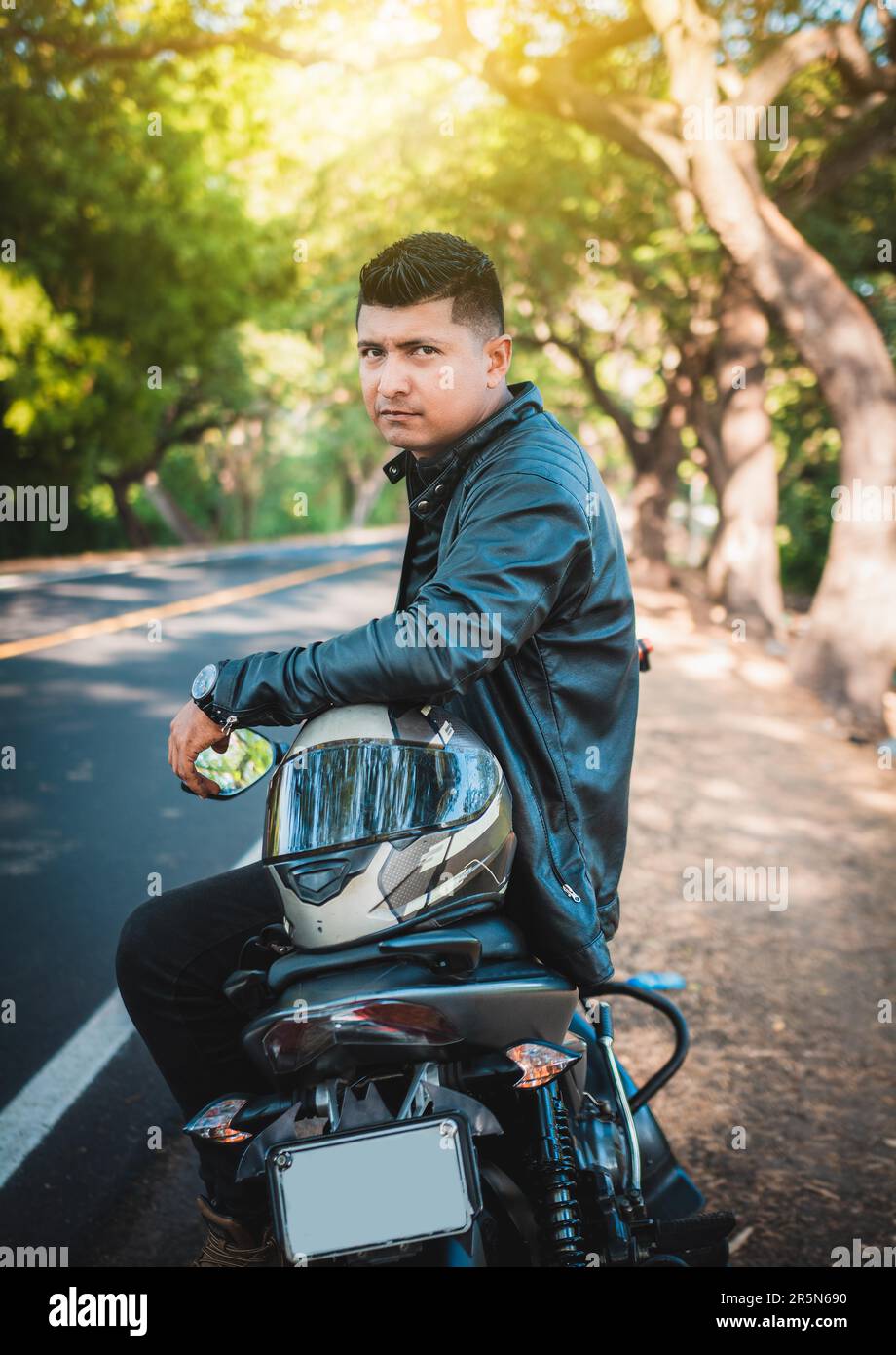 Portrait of handsome man sitting on his motorbike at the roadside ...