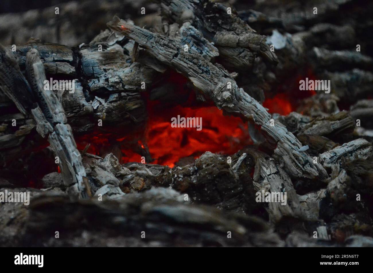 Glowing embers in hot red color. The hot embers of burning wood log fire. Firewood burning on ...