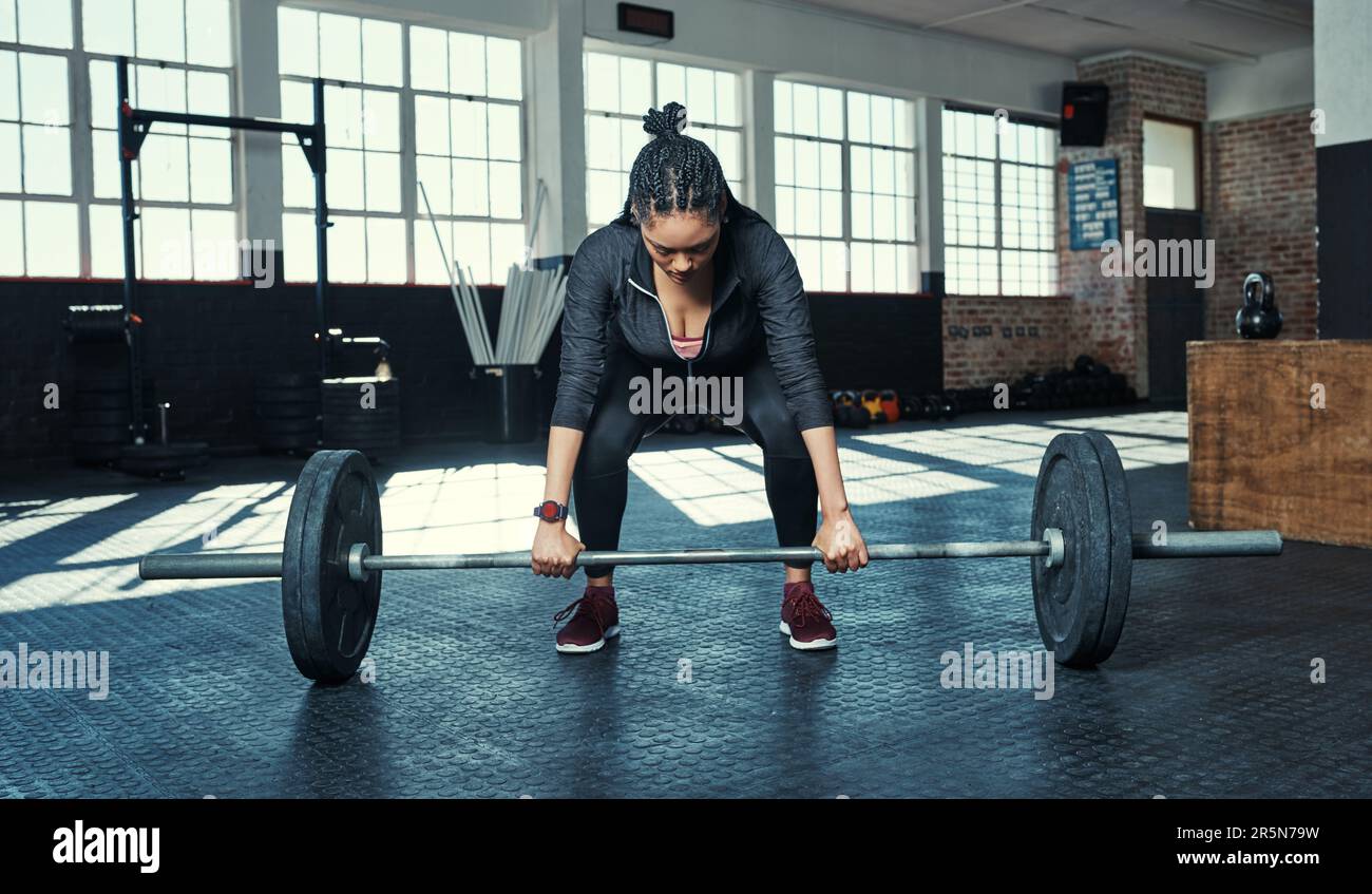 Lifting for strength. a young woman lifting weights in a gym Stock ...