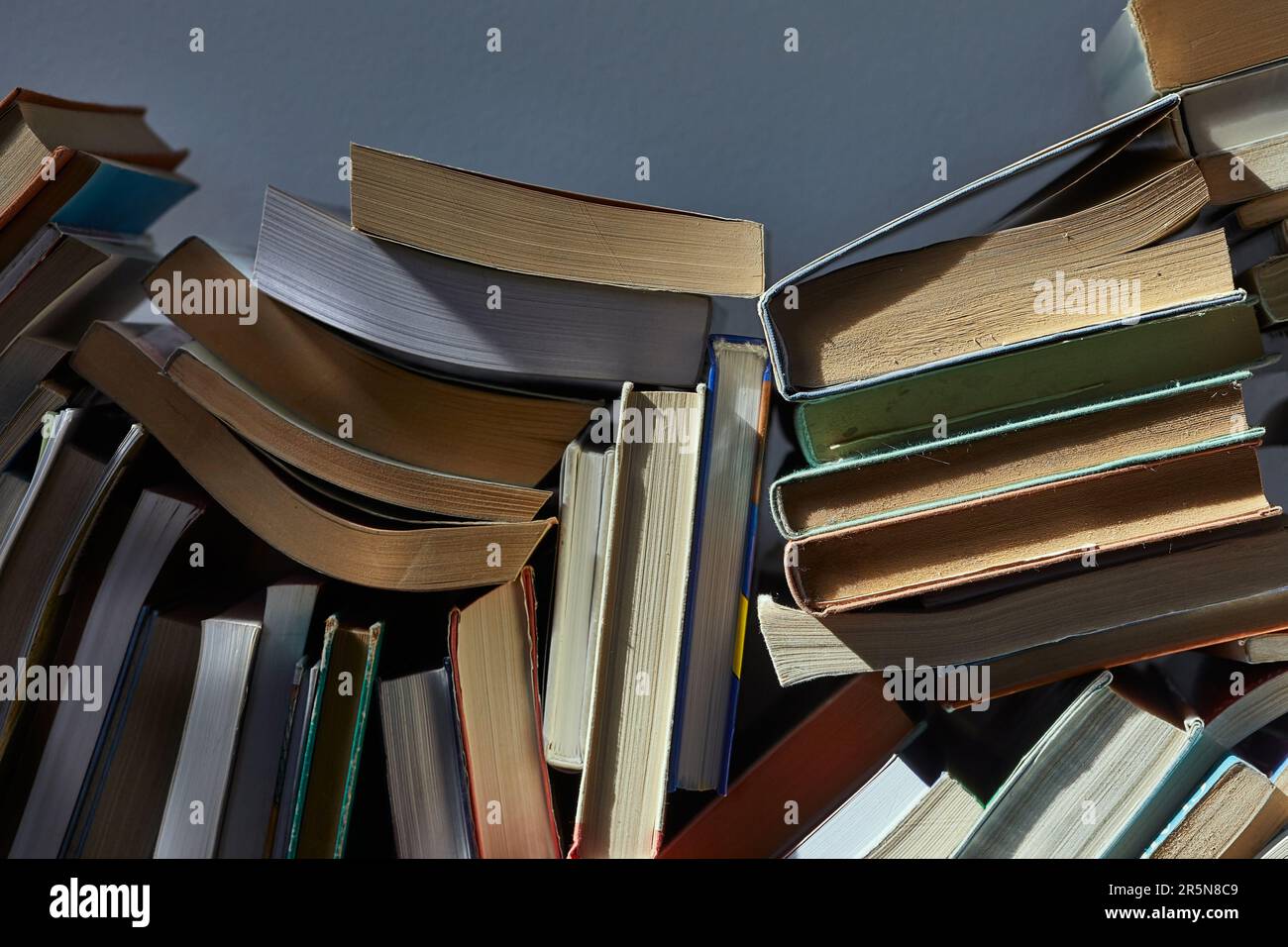 Wall of books piled up Stock Photo - Alamy