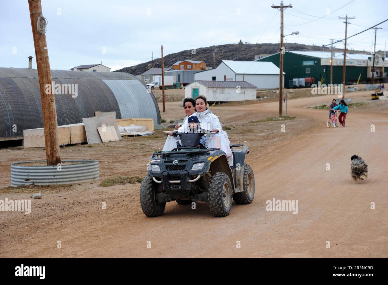 Inuit woman with child on quadbike, Qikiqtarjuaq village, Baffin Island ...