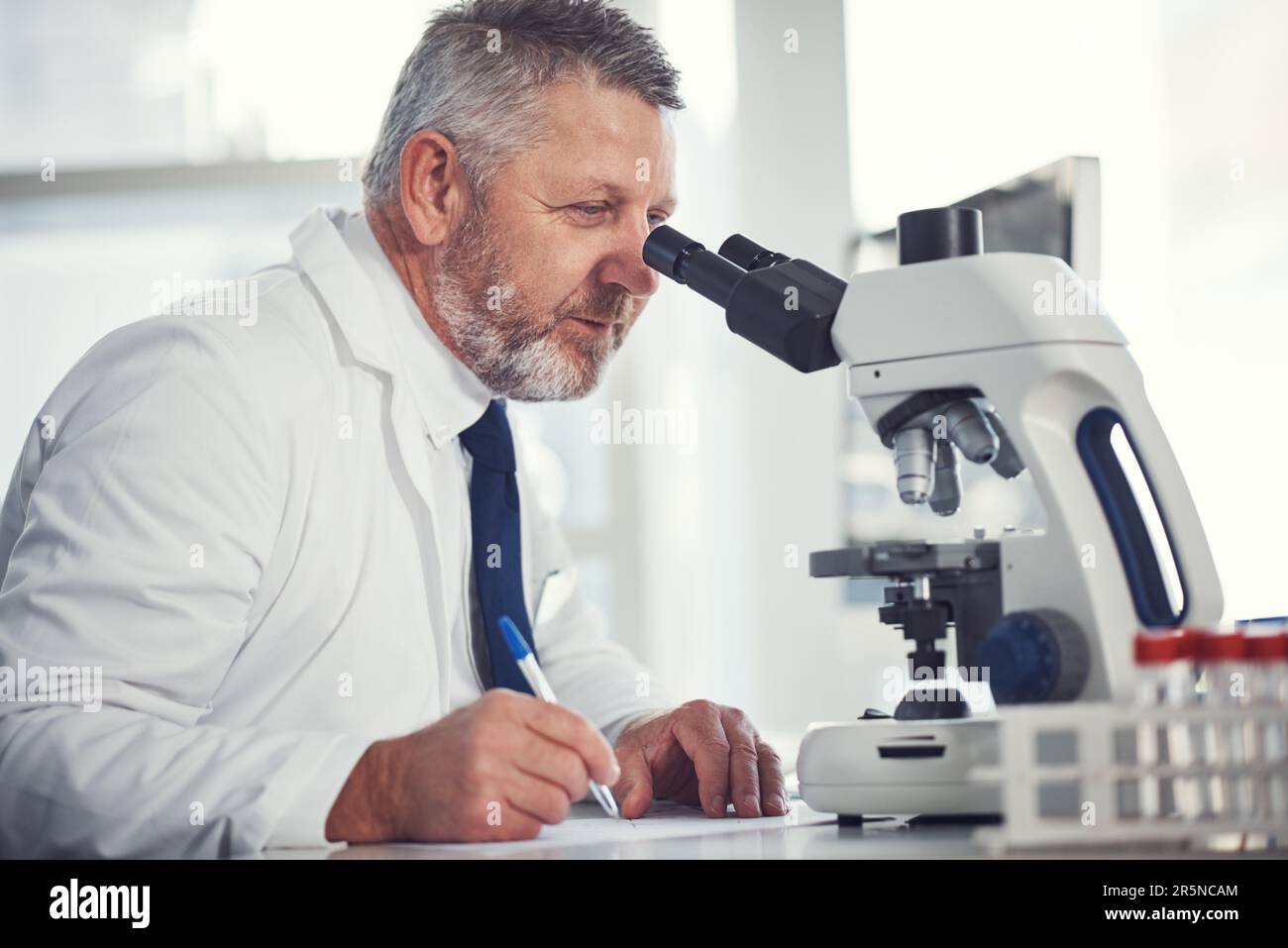 Lets see what we have here...a mature scientist using a microscope in a ...