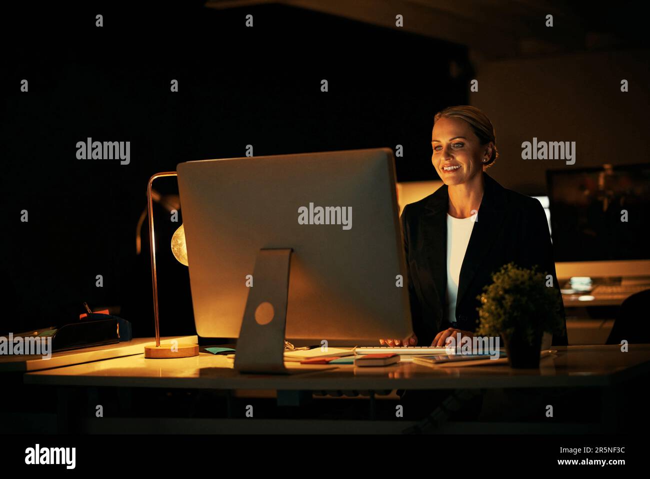 Working late into the night. a mature businesswoman working late at the ...