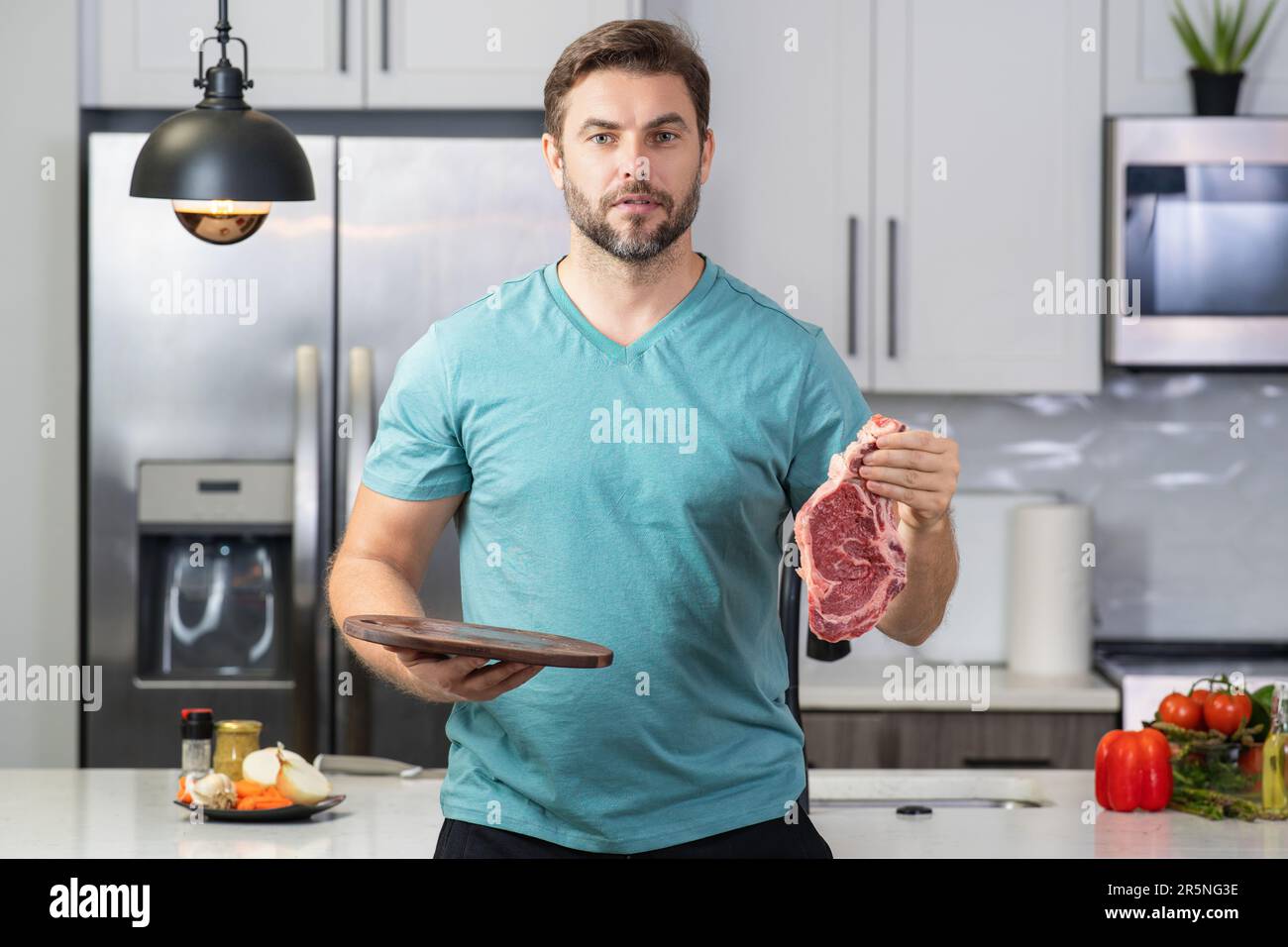 Chef with raw meat beef fillet on kitchen. Handsome man chef cooking ...