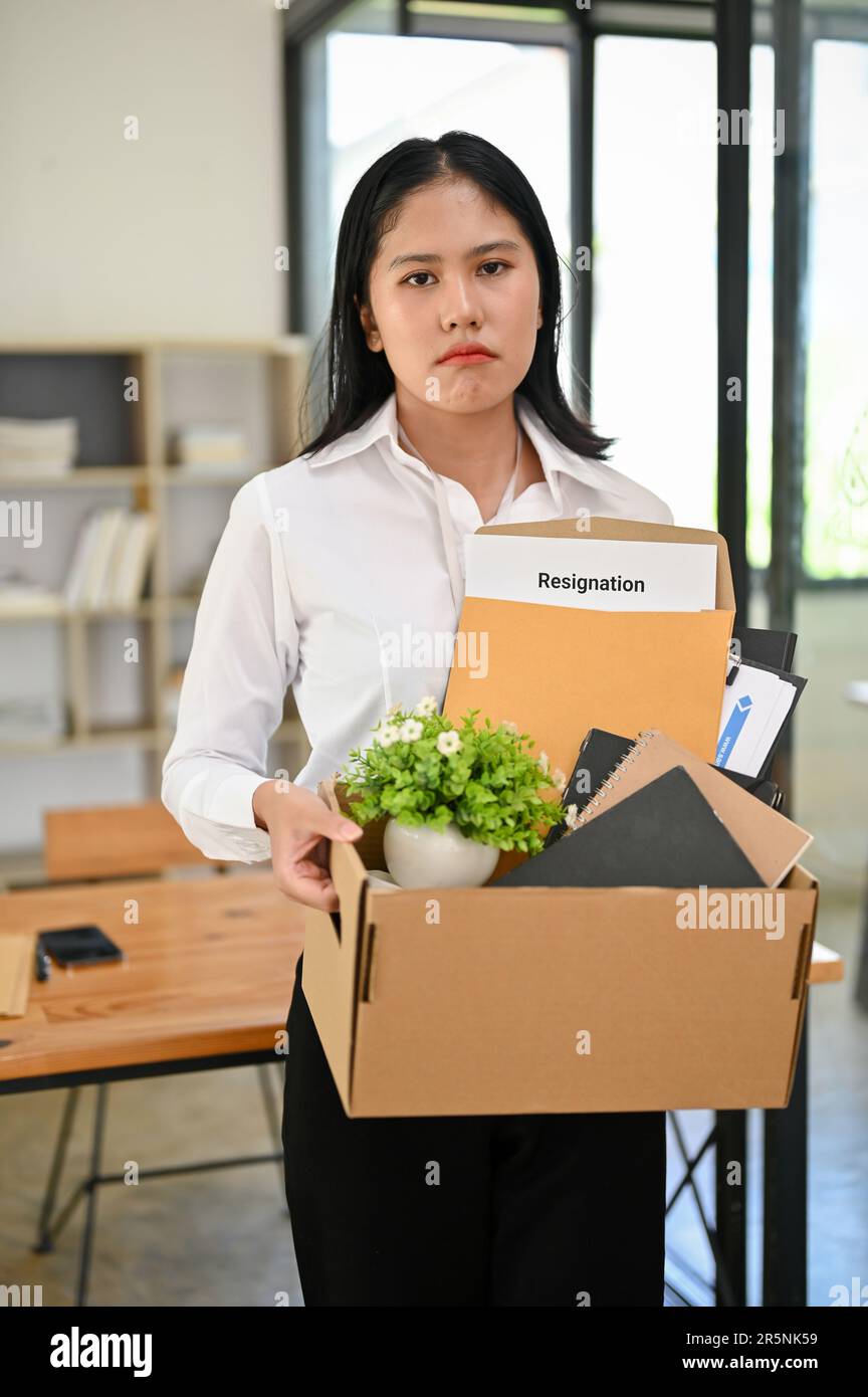 Sad and upset young Asian female office worker stands in the office ...