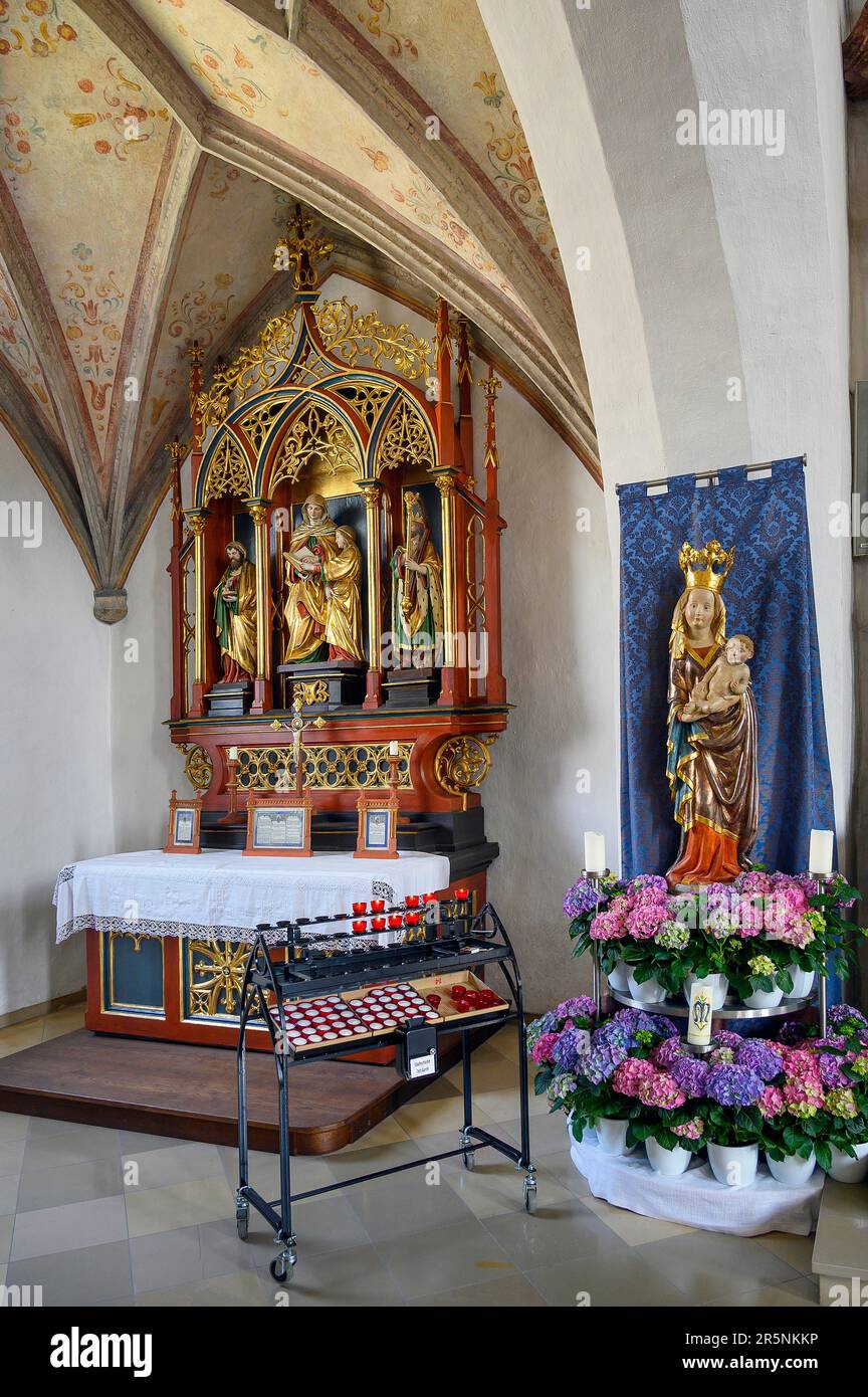 Side altar with Madonna figure, offering lights and flower decoration ...