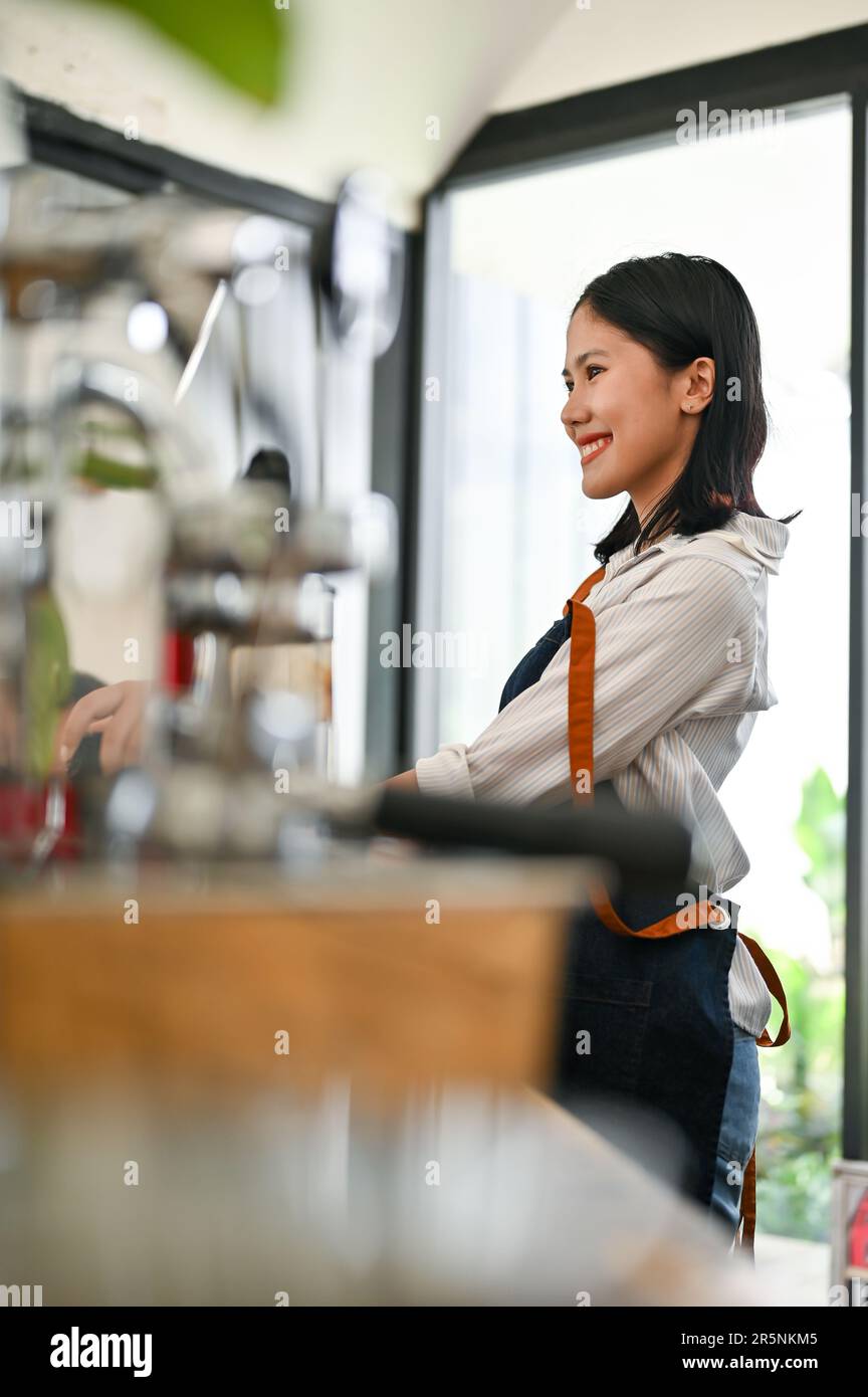 Rear view of a friendly and smiling young Asian female cashier or ...